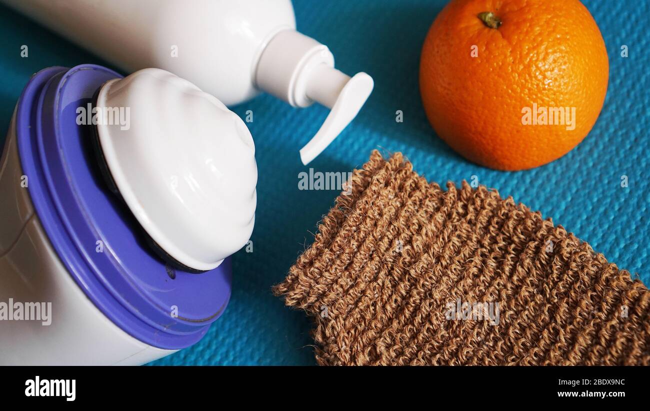 Lotion, orange, shower sponge and anti-cellulite massager on a blue ...