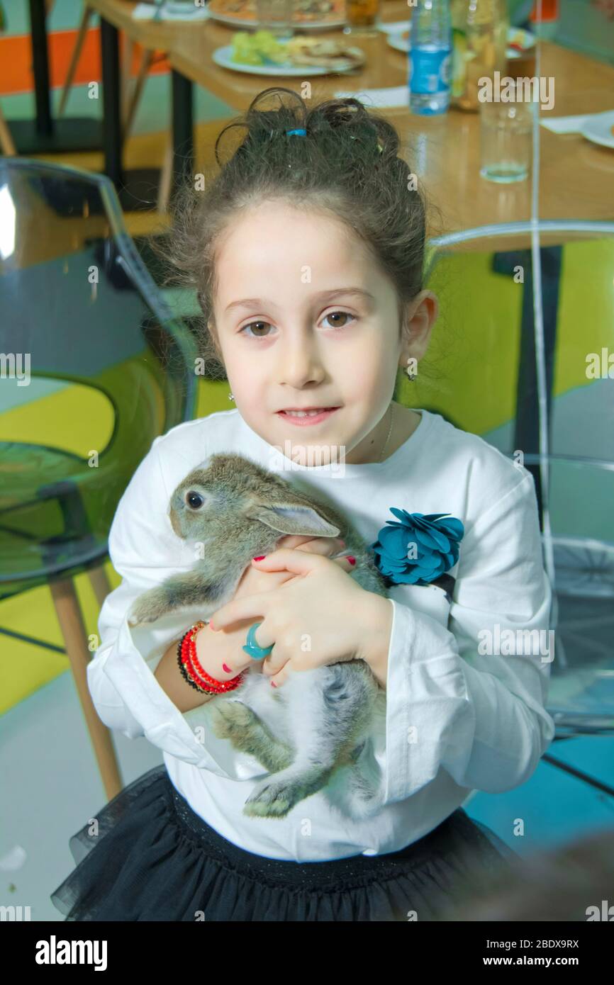 The child is holding a rabbit . Happy young girl holding rabbit ...