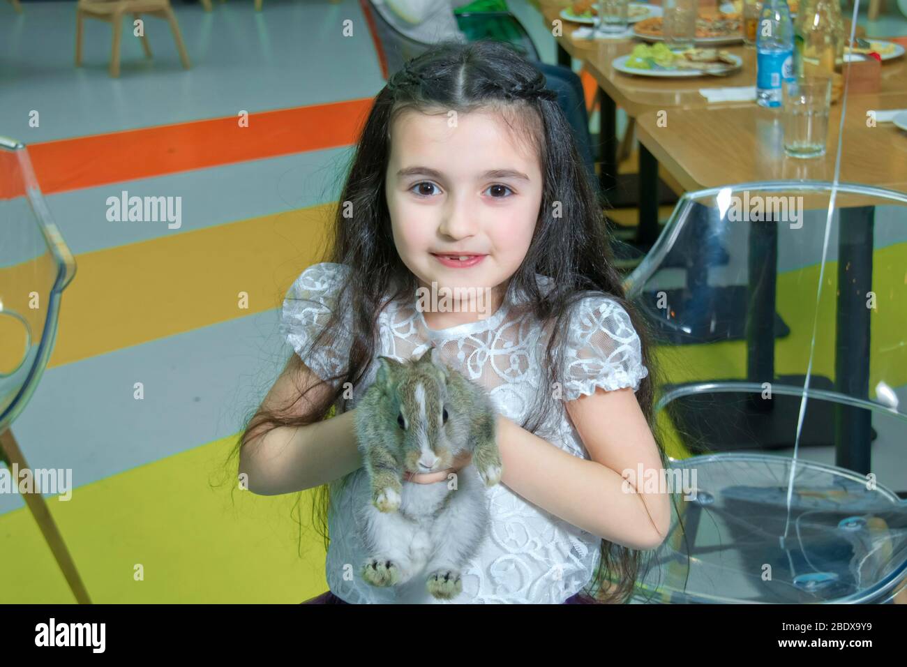 The child is holding a rabbit . Happy young girl holding rabbit ...