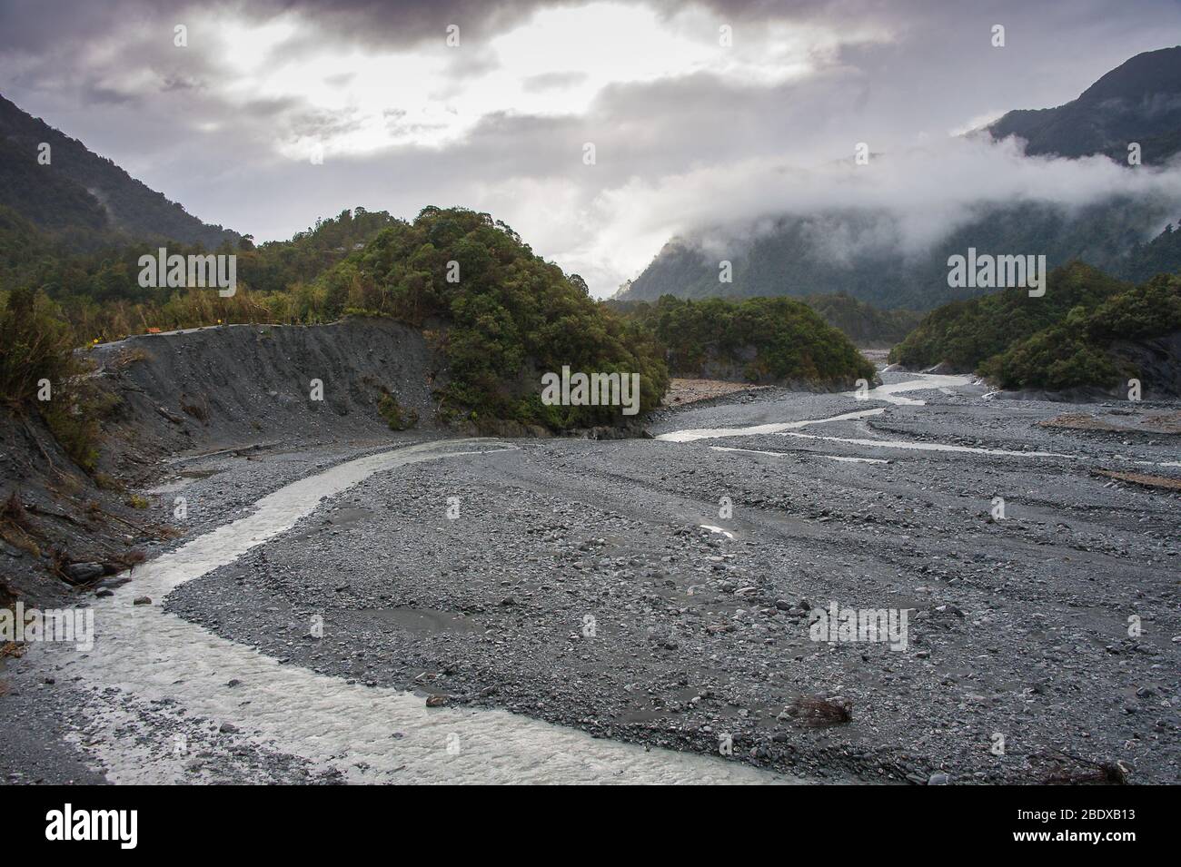 Franz Josef Glacier and headstream of the Waiho River. Rain cloud hangs ...