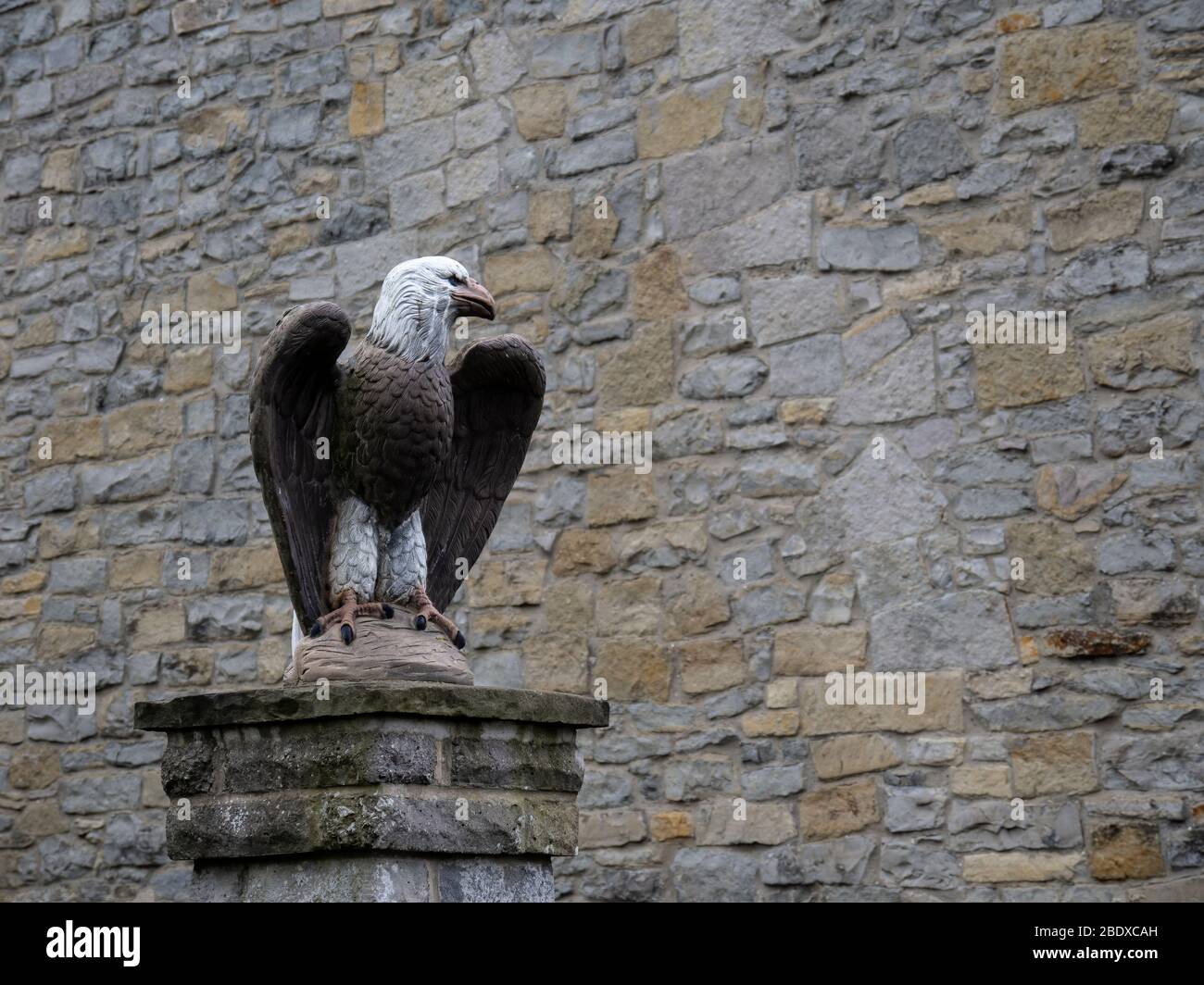 Old carved stone eagle sculpture on pillar by wall. With copyspace ...