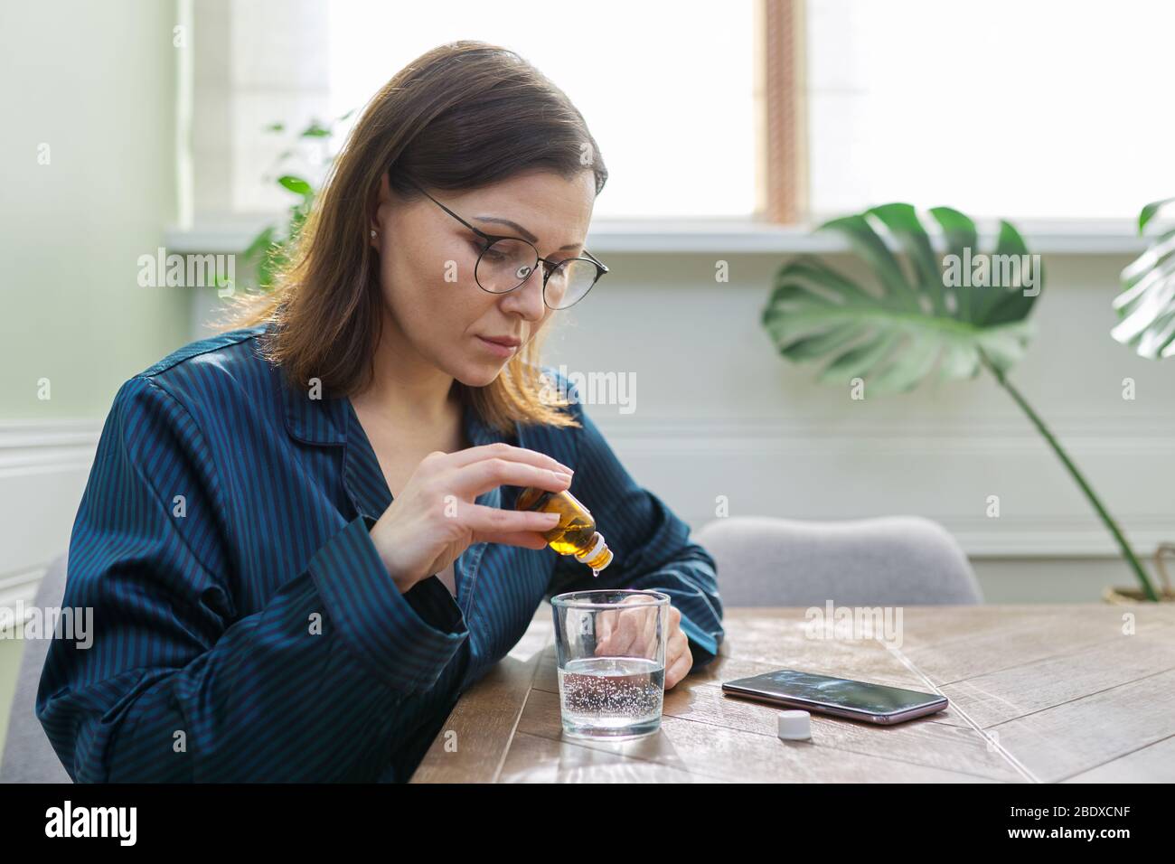 Mature Woman Dripping Drops With Glass Of Water Drinking Sedative