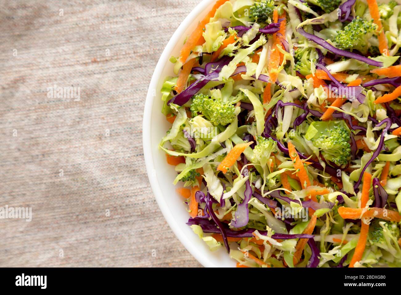 Homemade Raw Shredded Broccoli Slaw in a white bowl on cloth, top view ...