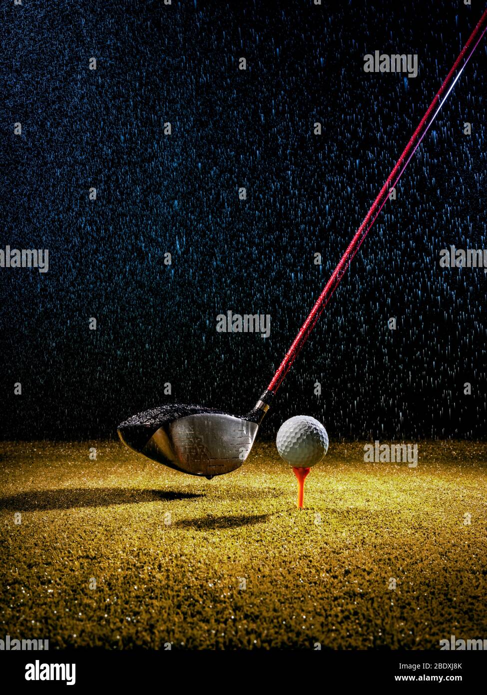 Beam of light in the rain illuminating a golf driver and golf ball on ...