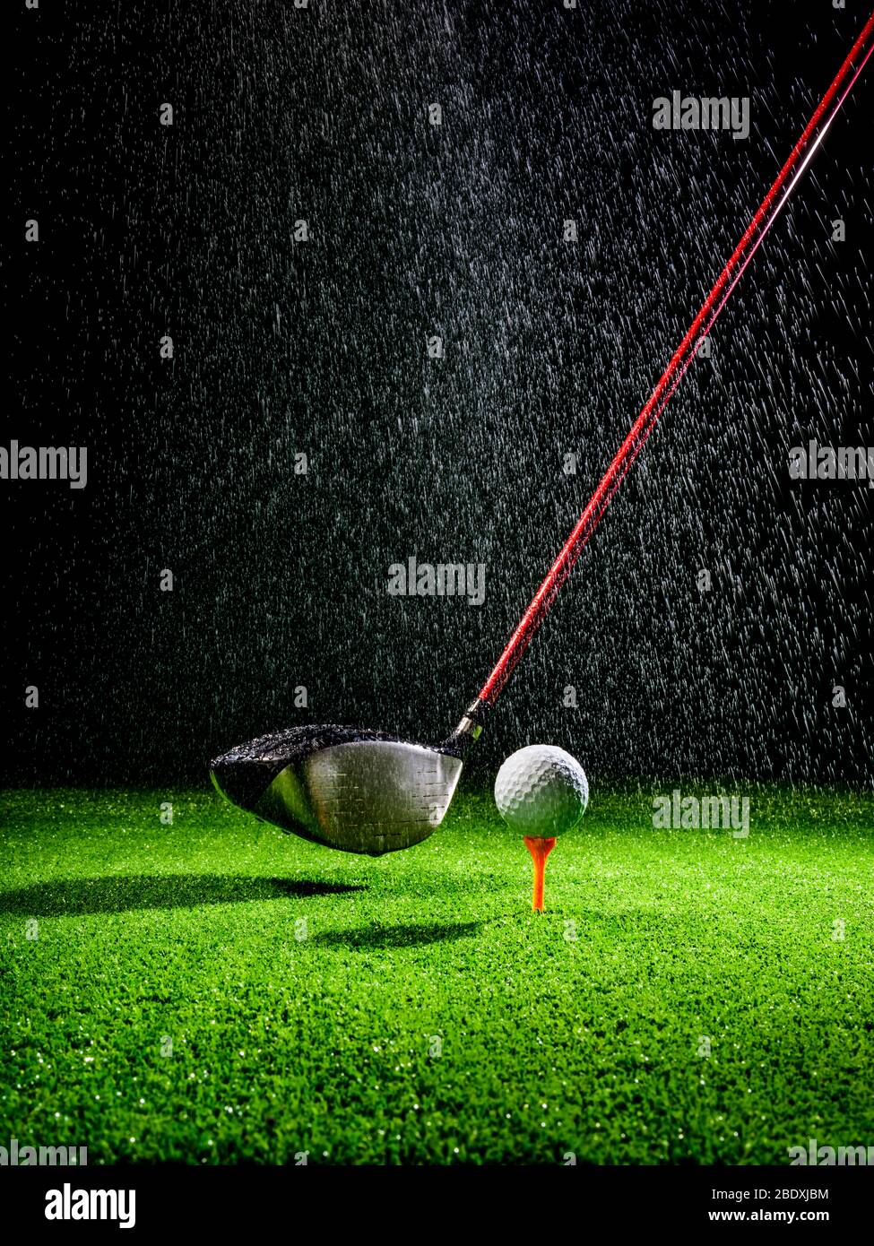 Beam of light in the rain illuminating a golf driver and golf ball on ...