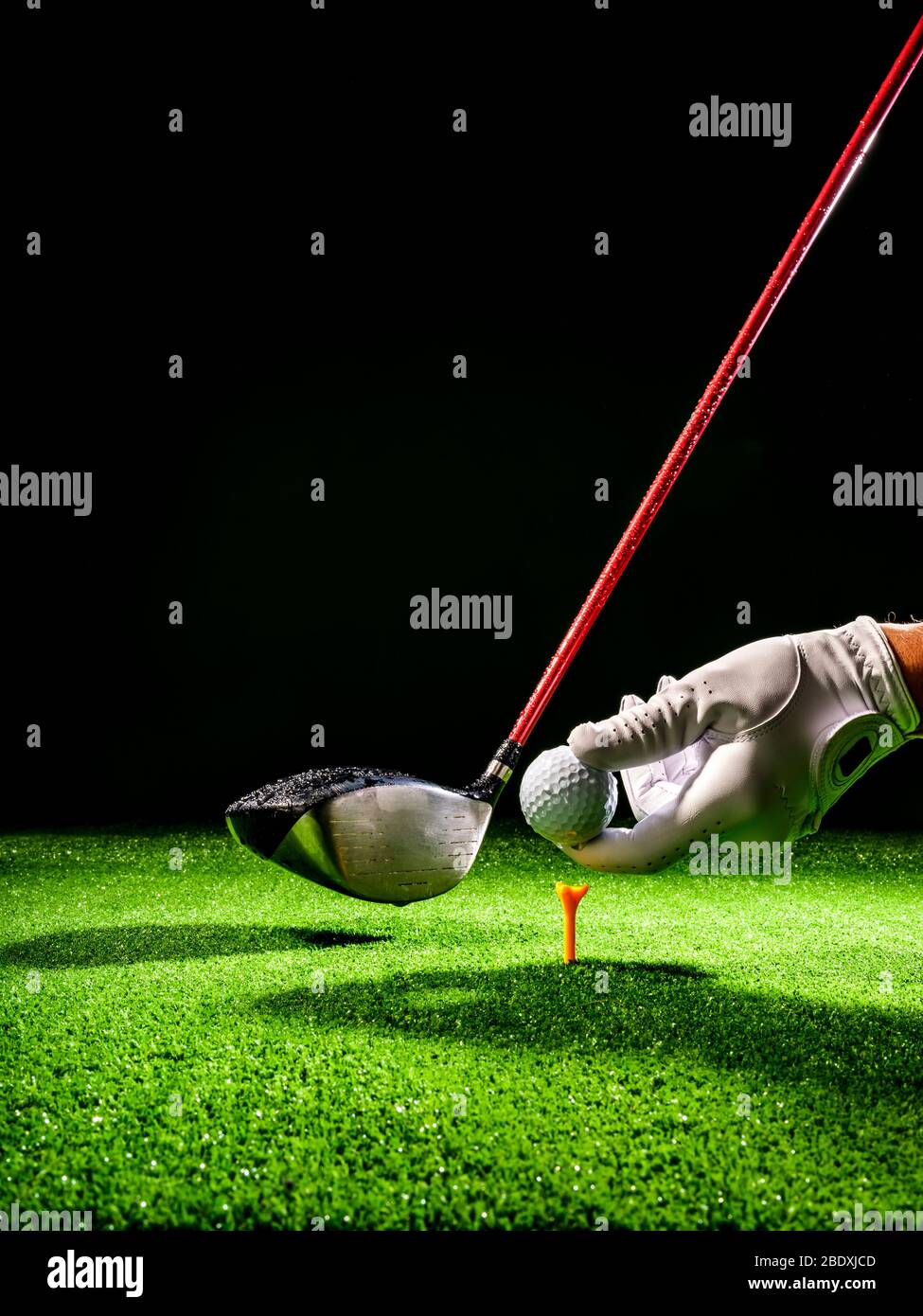 Golf ball positioned on the tee of a golf course with a golf driver on ...