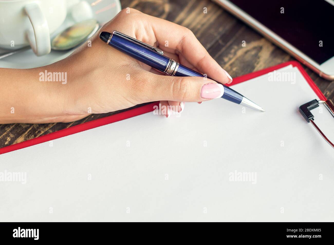 Left handed woman hand making notes in the notepad at cafe. Mock up ...