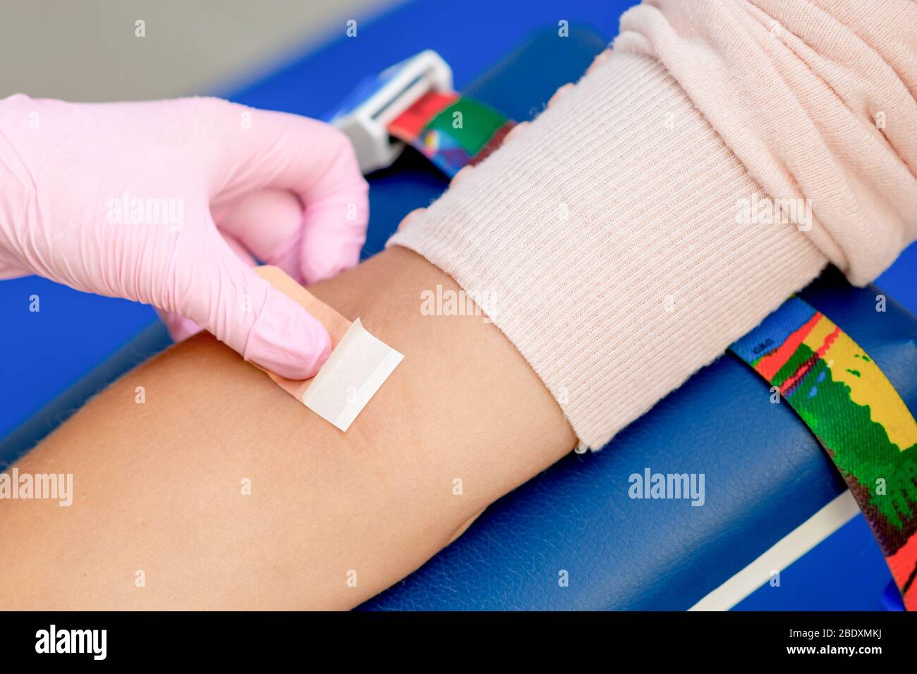 Doctor in rubber protective gloves glues an adhesive plaster on arm ...