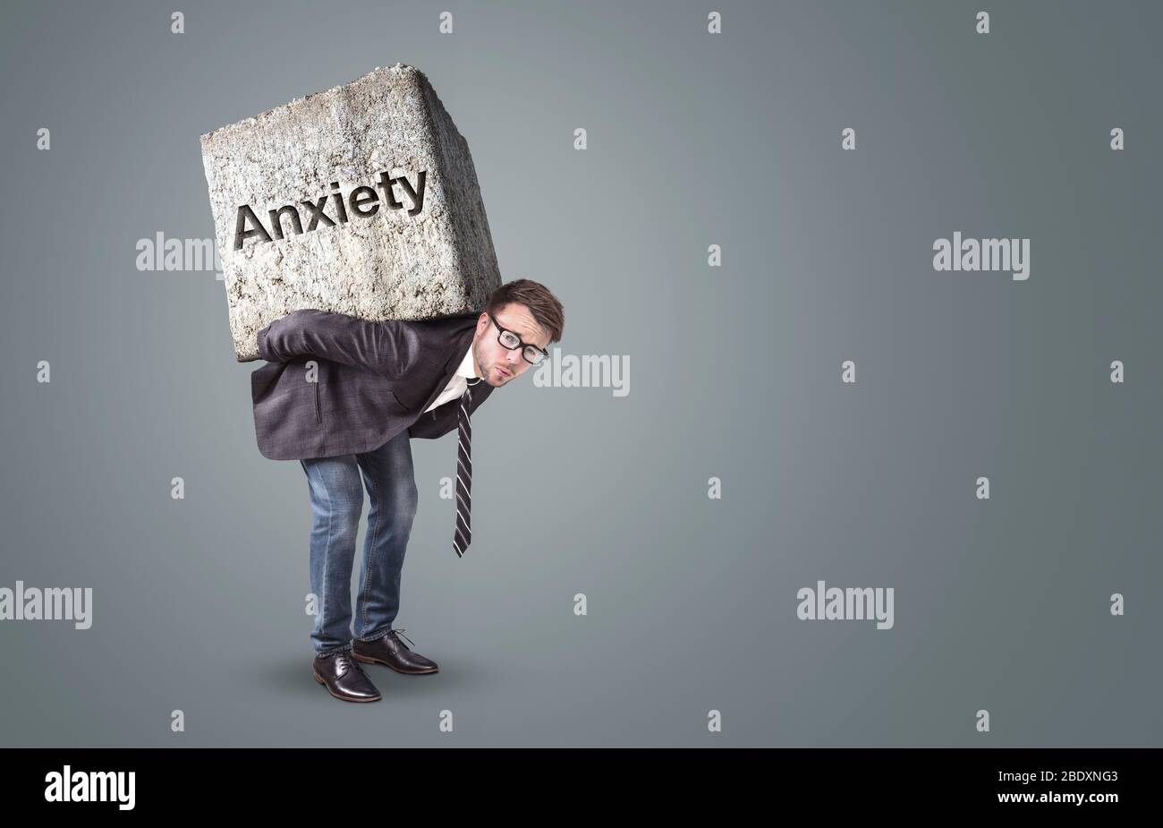 Man carrying a heavy stone labeled with Anxiety Stock Photo - Alamy