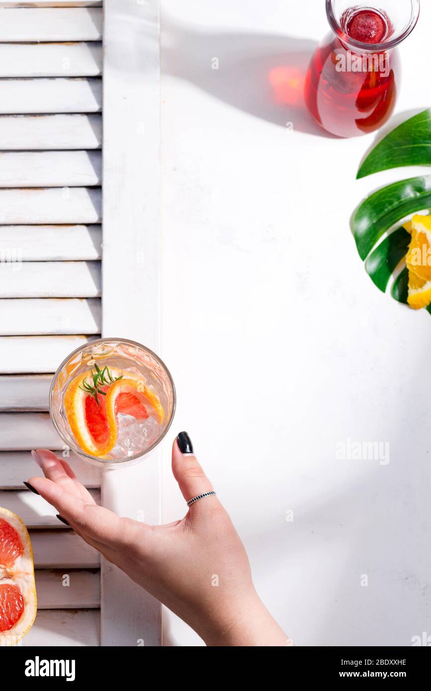 Female's hand takes a glass of homemade fruit cold cocktail with slice ...