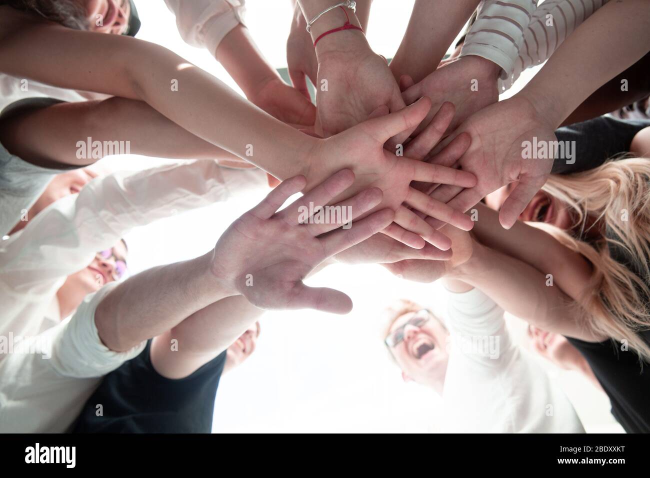 bottom view . a team of young people making a tower out of their hands ...