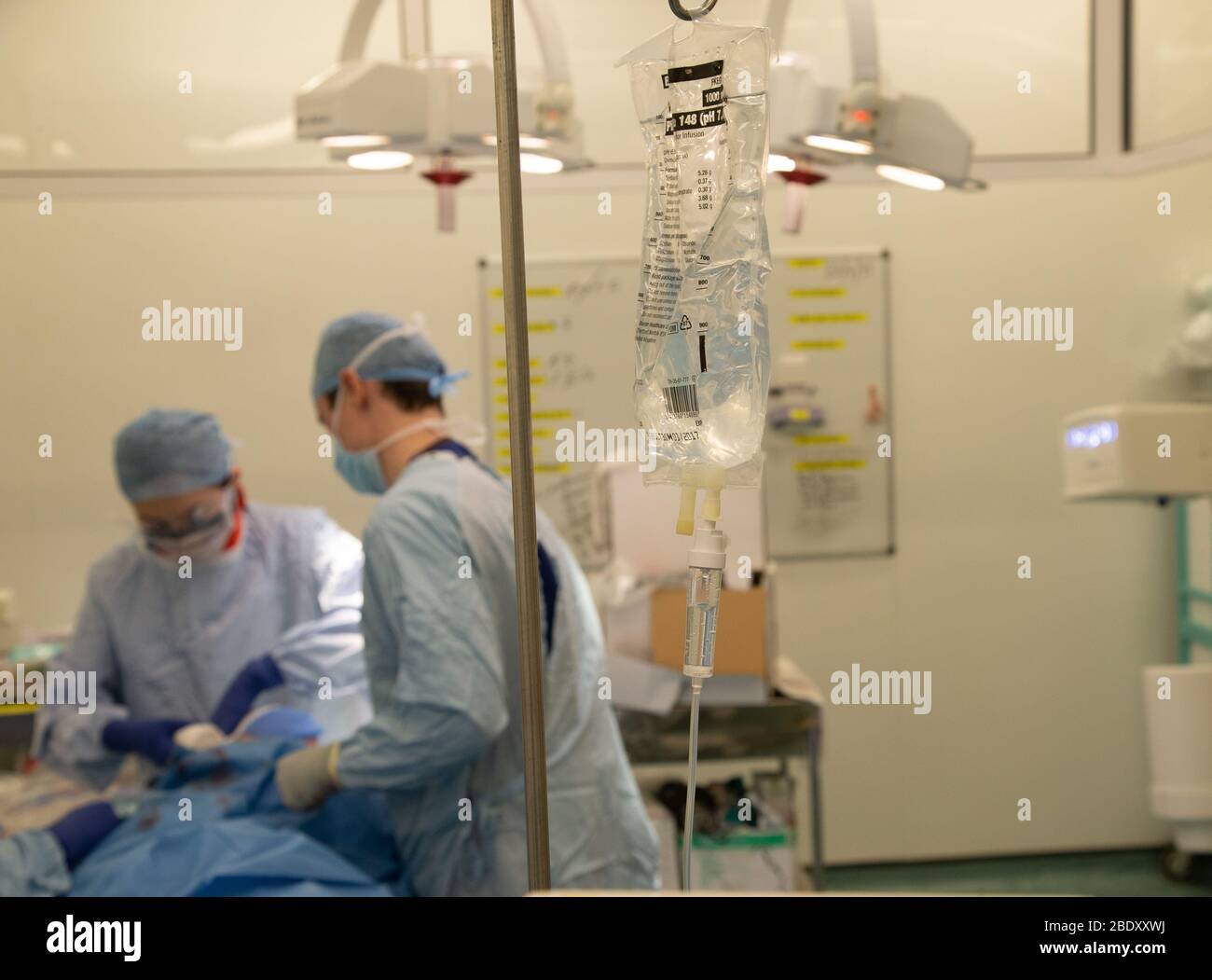 A saline drip in an NHS operating theatre as surgeons perform an ...