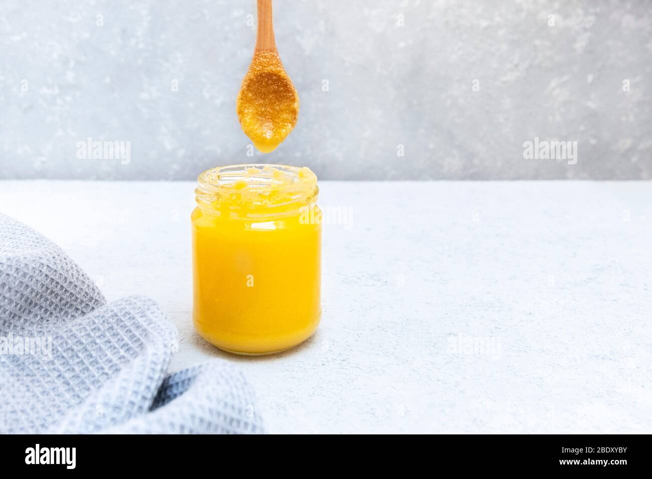 Indian desi ghee or clarified liquid butter in glass jar on neutral ...