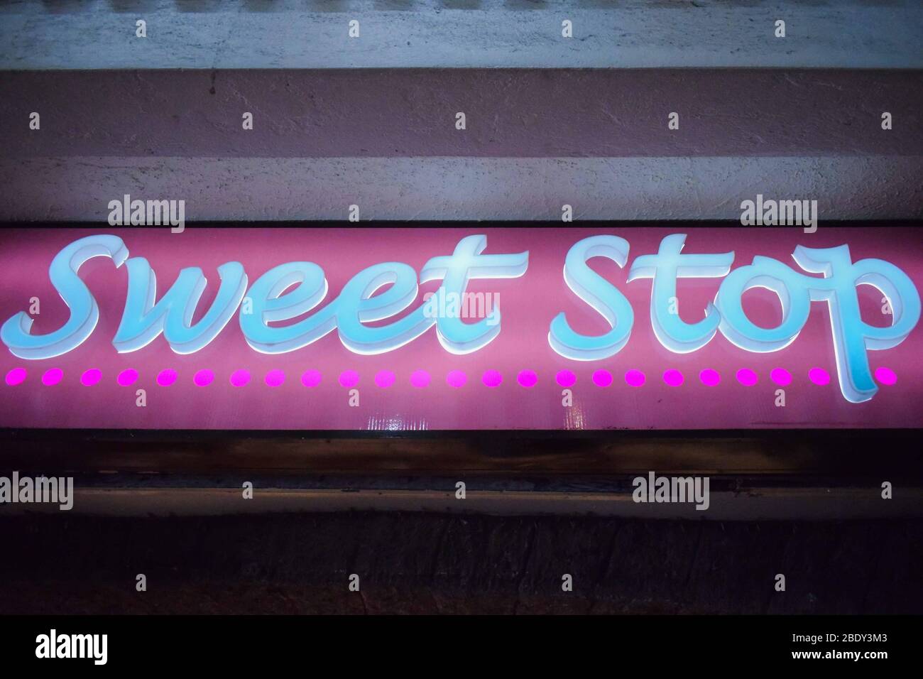 Lit sweet stop signage on a pink background. Neon lights Stock Photo ...