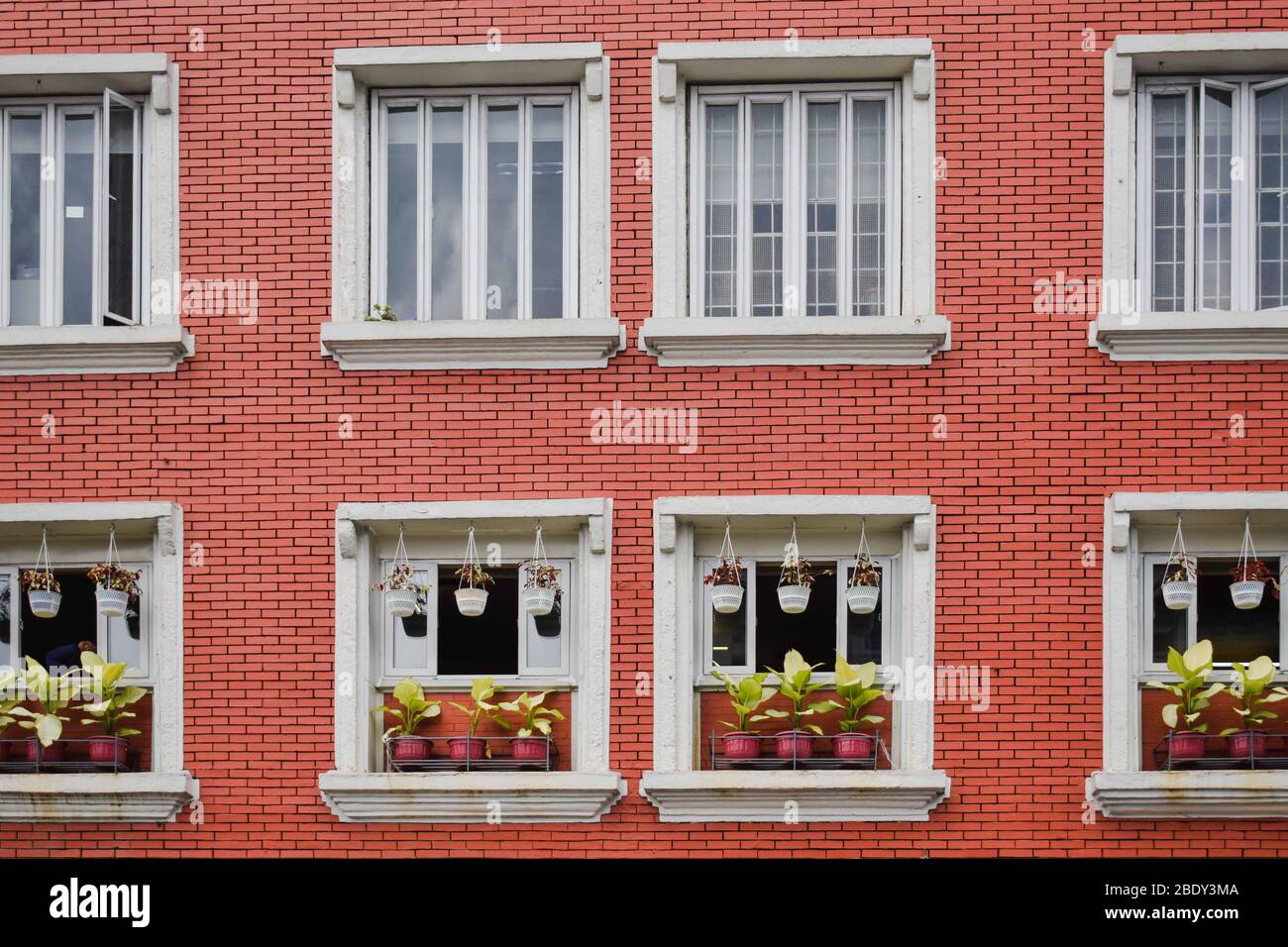 Brick house with white painted windows and flower pots hanging at the ...