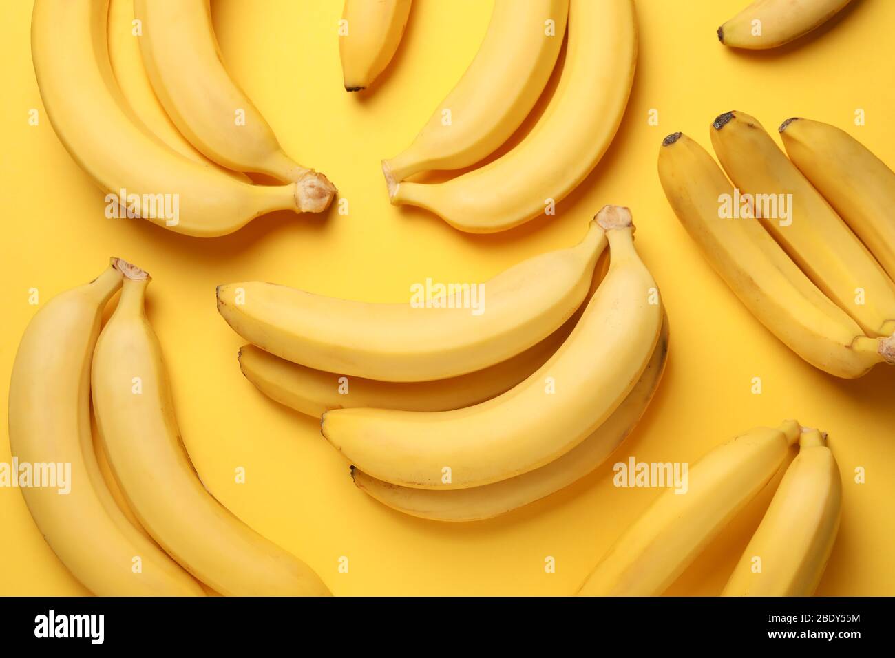 Banana clusters on yellow background. Fresh fruit Stock Photo - Alamy