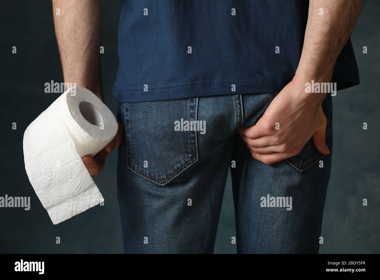 Man has diarrhea. Man holds toilet paper on blue background Stock Photo ...
