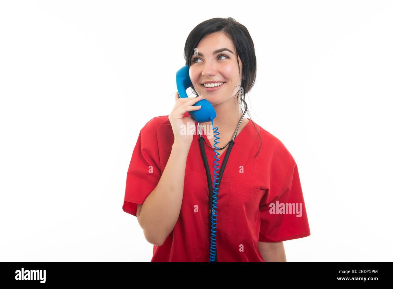 Portrait of young attractive female nurse talking at telephone receiver ...