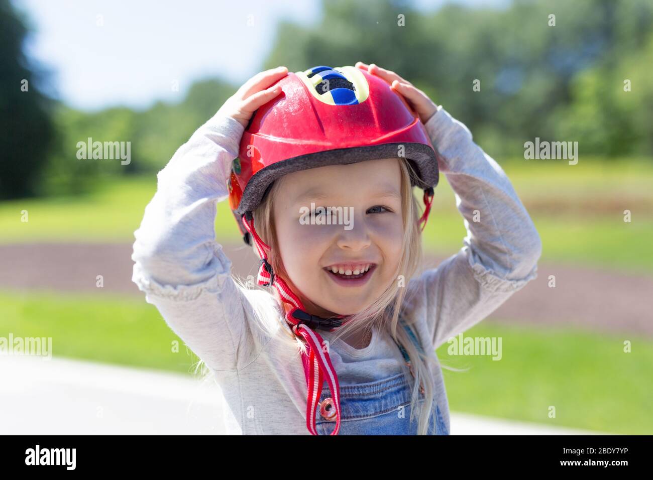 Happy toddler girl wearing red plastic helmet outdoors Stock Photo - Alamy