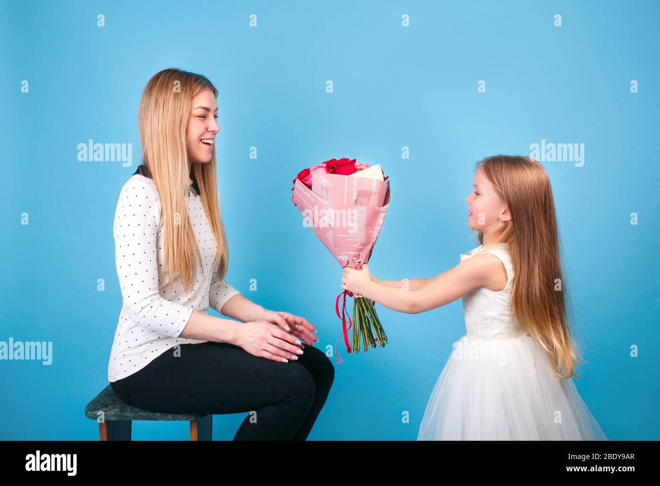 Little daughter congratulates mother and gives a bouquet of roses ...