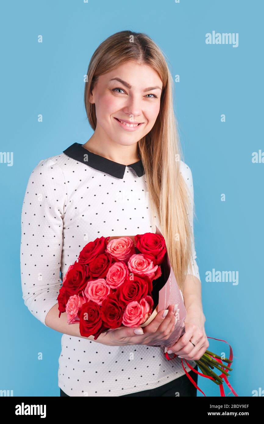 Happy beautiful woman with bouquet of red roses smilling over blue ...