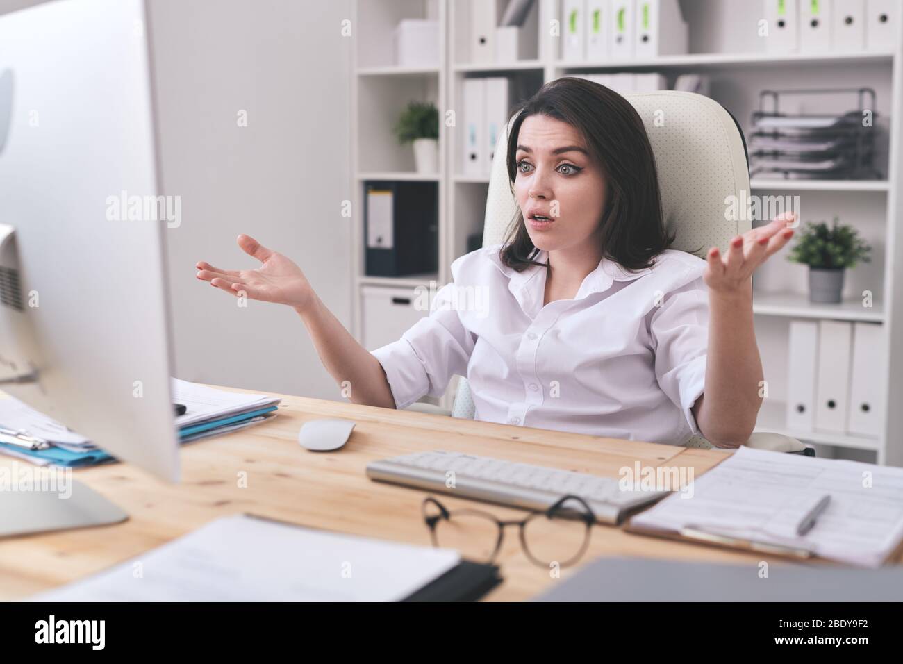 Young surprised businesswoman with outstretched hands looking at ...
