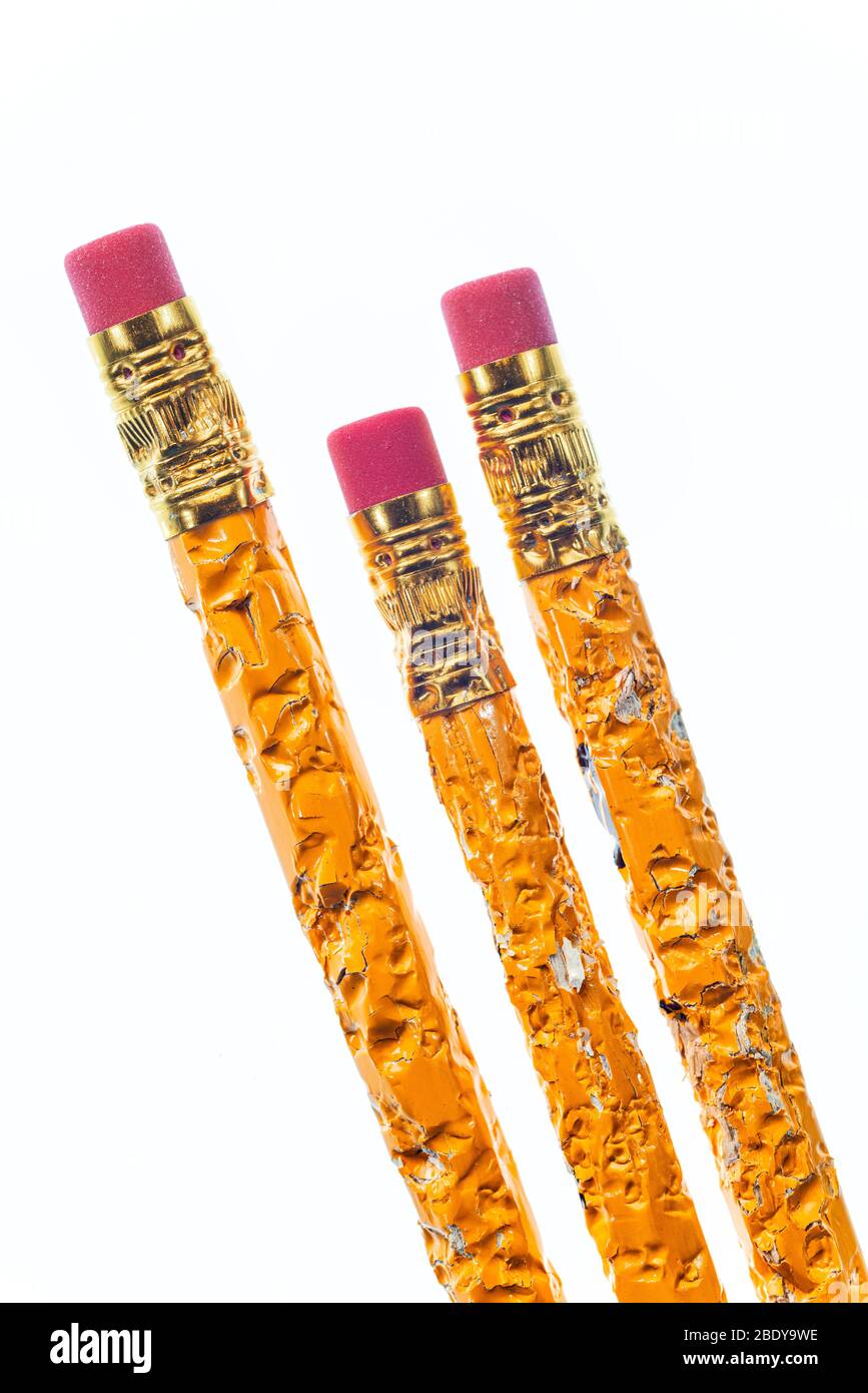 Vertical shot of the eraser end of three chewed pencils on a white ...