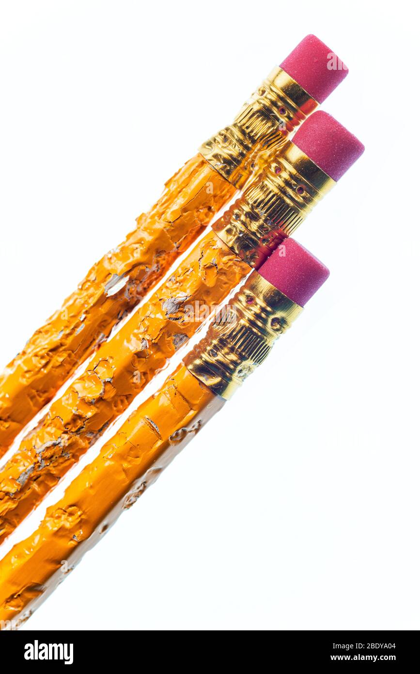 Vertical shot of the eraser end of three chewed pencils on a white ...