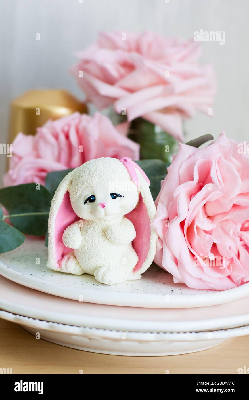 White chocolate bunny with pink ears with roses and golden candle on ...