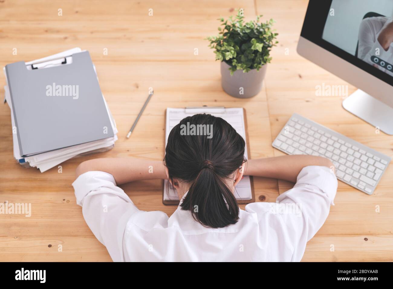 Back view of young tired businesswoman lying on desk with her face on ...