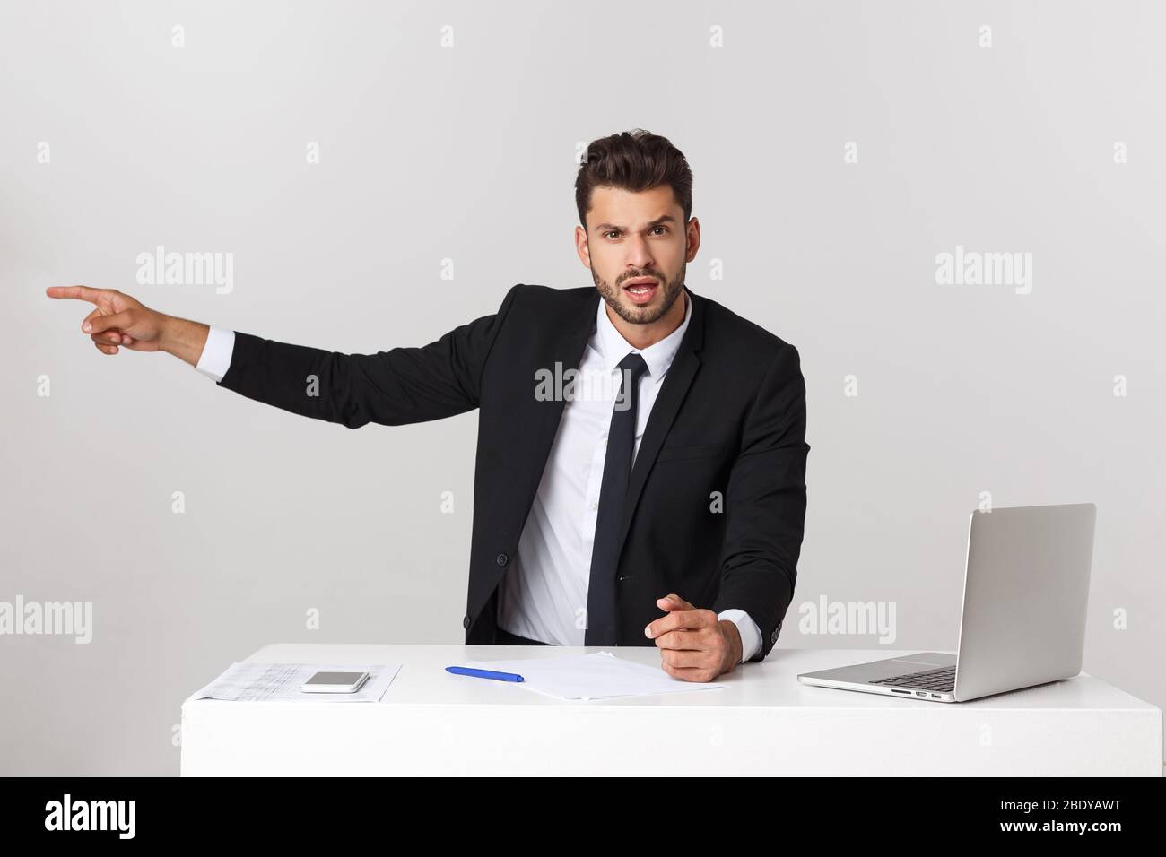 Angry businessman sitting at the table and screaming over gray ...