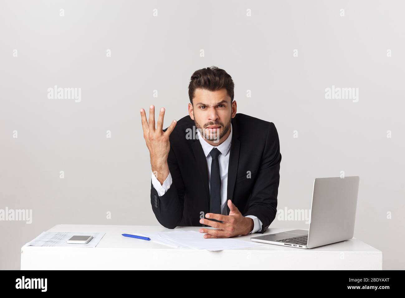 Angry businessman sitting at the table and screaming over gray ...