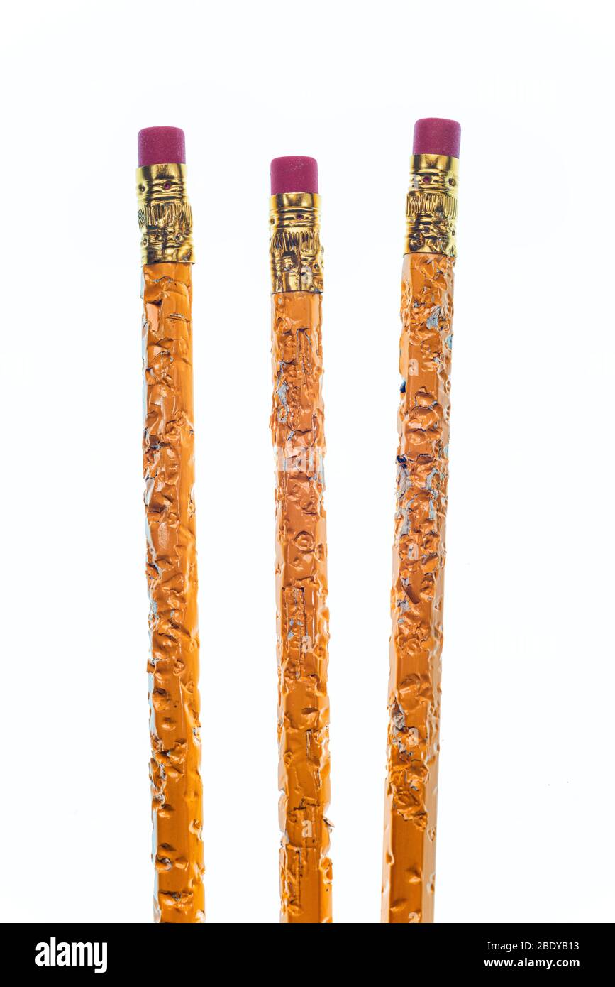 Vertical shot of the eraser end of three chewed pencils on a white ...