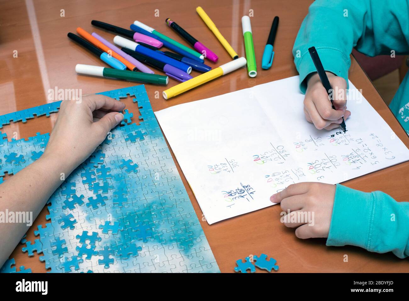 Some hands do a puzzle and other children's hands do math Stock Photo ...