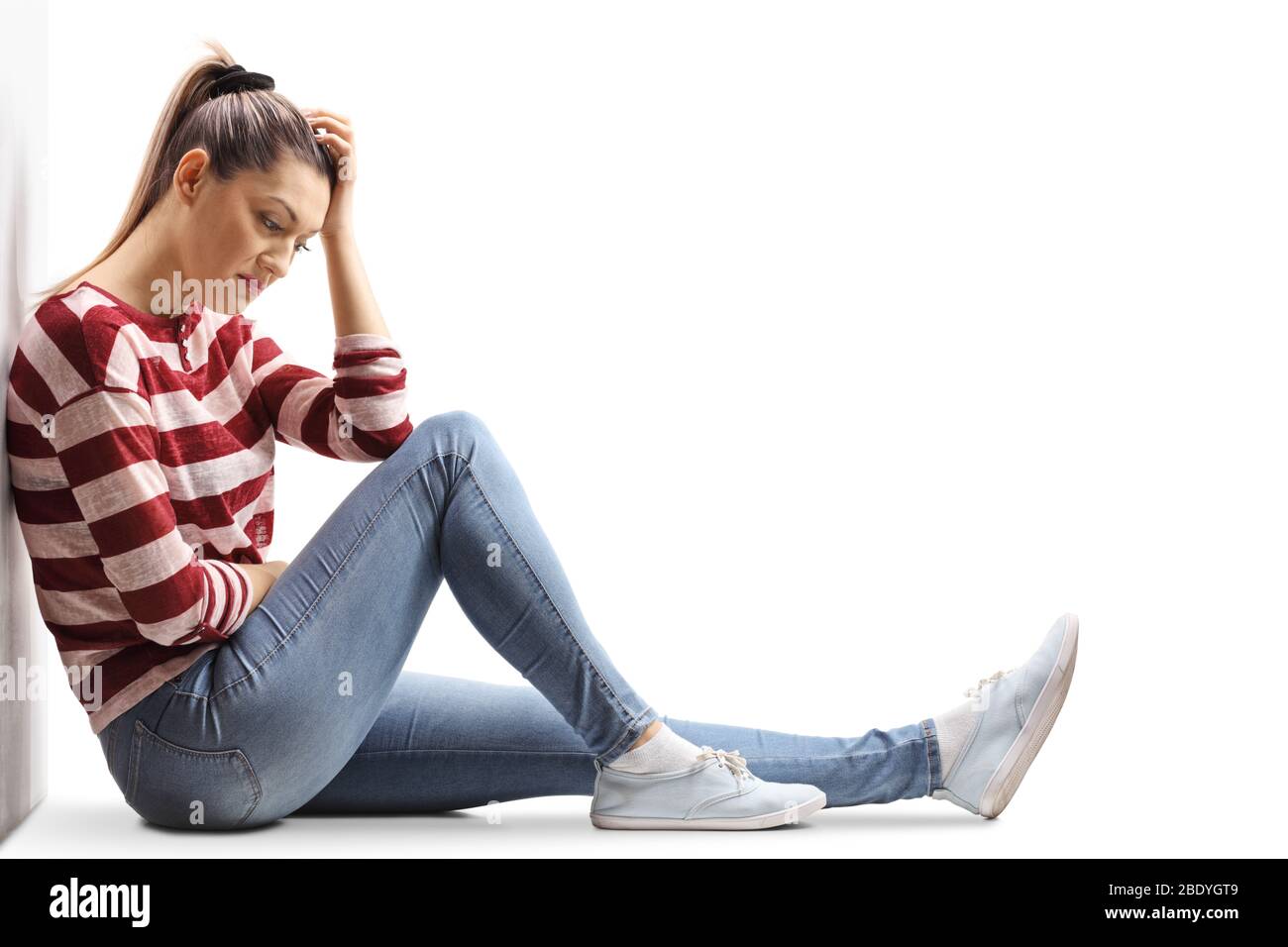 Sad young woman sitting on the floor with head down isolated on white ...