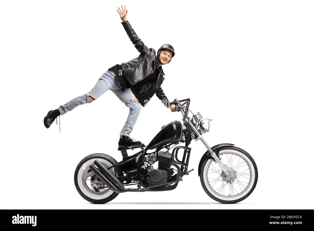 Young daredevil standing on the seat and riding a chopper motorbike ...
