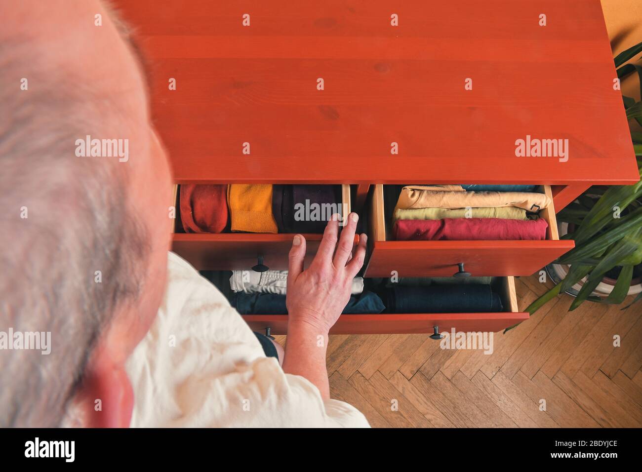 Man organizing clothes in wardrobe. Man choosing orderly folded socks ...