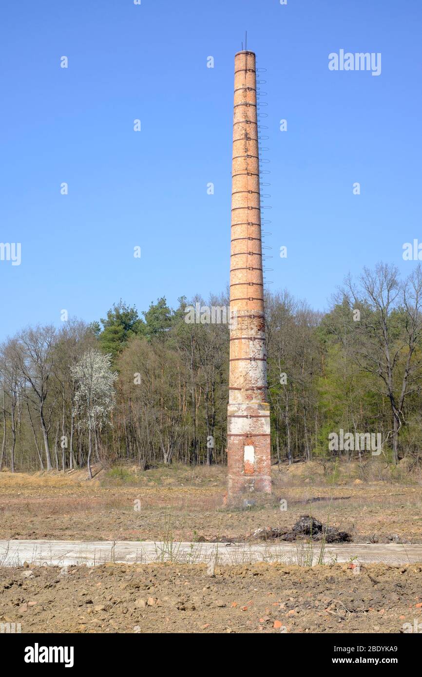 tall industrial chimney stack stands alone in the centre of an empty ...