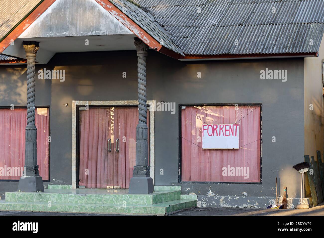For rent signboard on a gray one-story house with large curtained ...