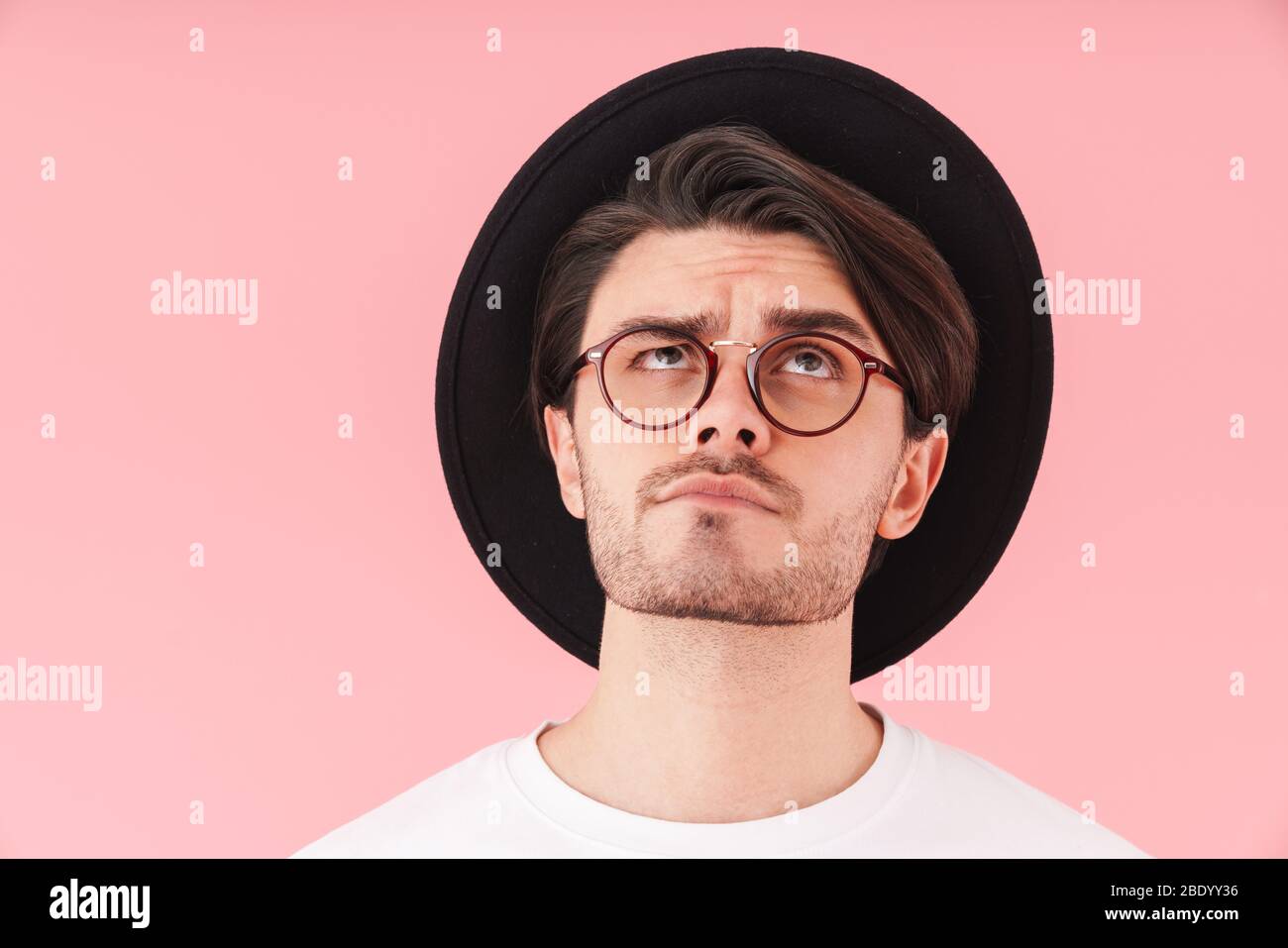 Image of uptight man wearing eyeglasses and hat looking upward at ...