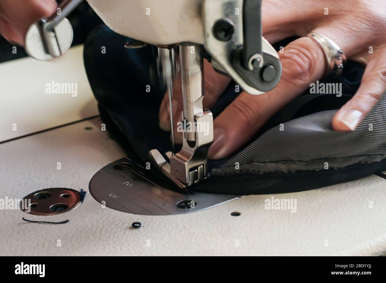 Needle and foot of sewing machine closeup as manufactoring background ...