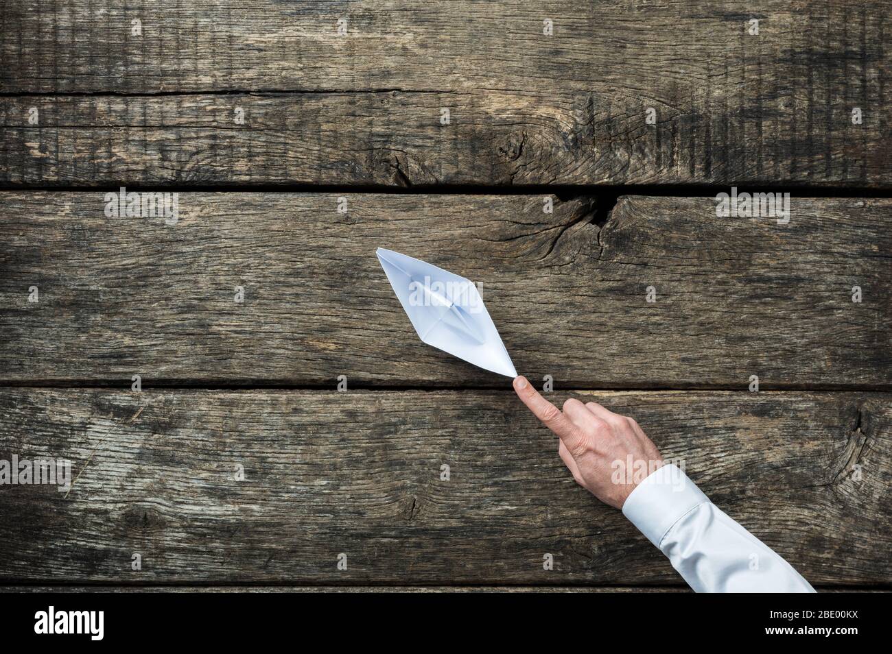 Top view of businessman pushing forward paper made origami boat in a ...