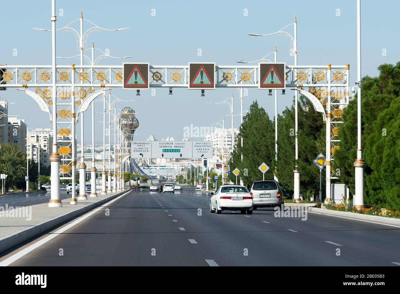 Avenue with overhead road signs decorated with gold. Street traffic or ...