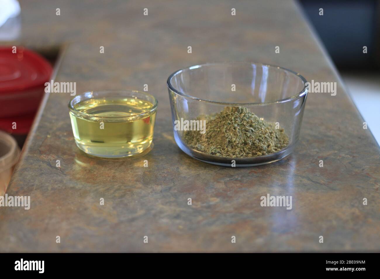 Ground up marijuana next to olive oil being prepared to make cannaoil ...