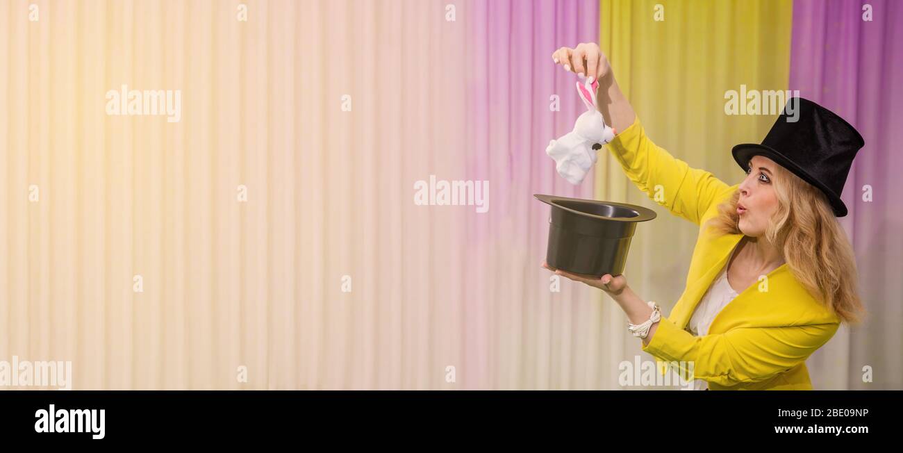 Female magician shows tricks takes a rabbit out of a hat. Woman ...