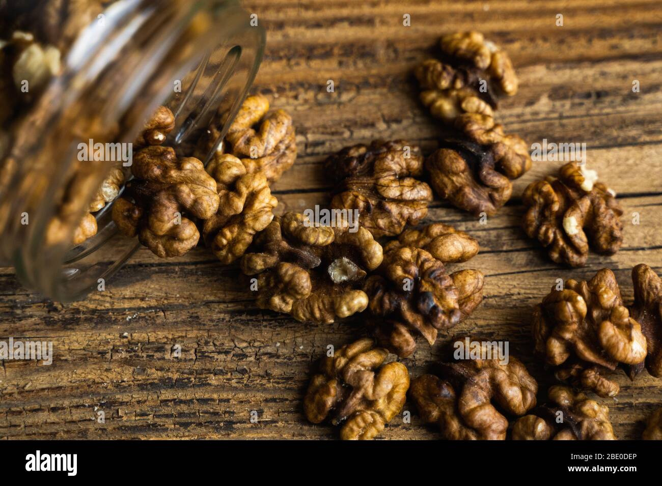 Walnut scattered on the wooden vintage table from a jar. Walnut is a ...