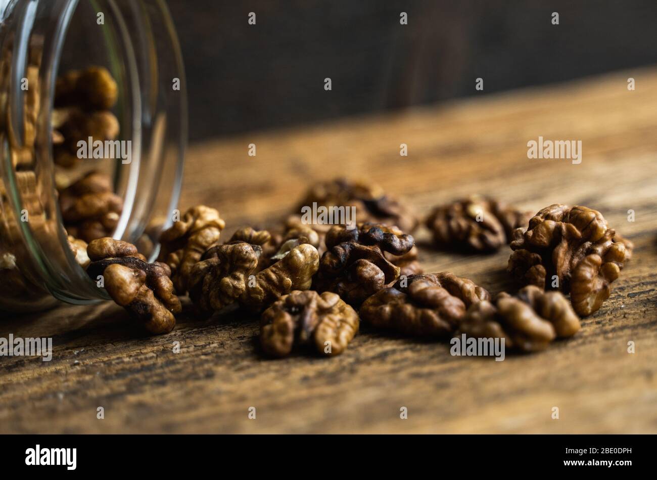 Walnut scattered on the wooden vintage table from a jar. Walnut is a ...