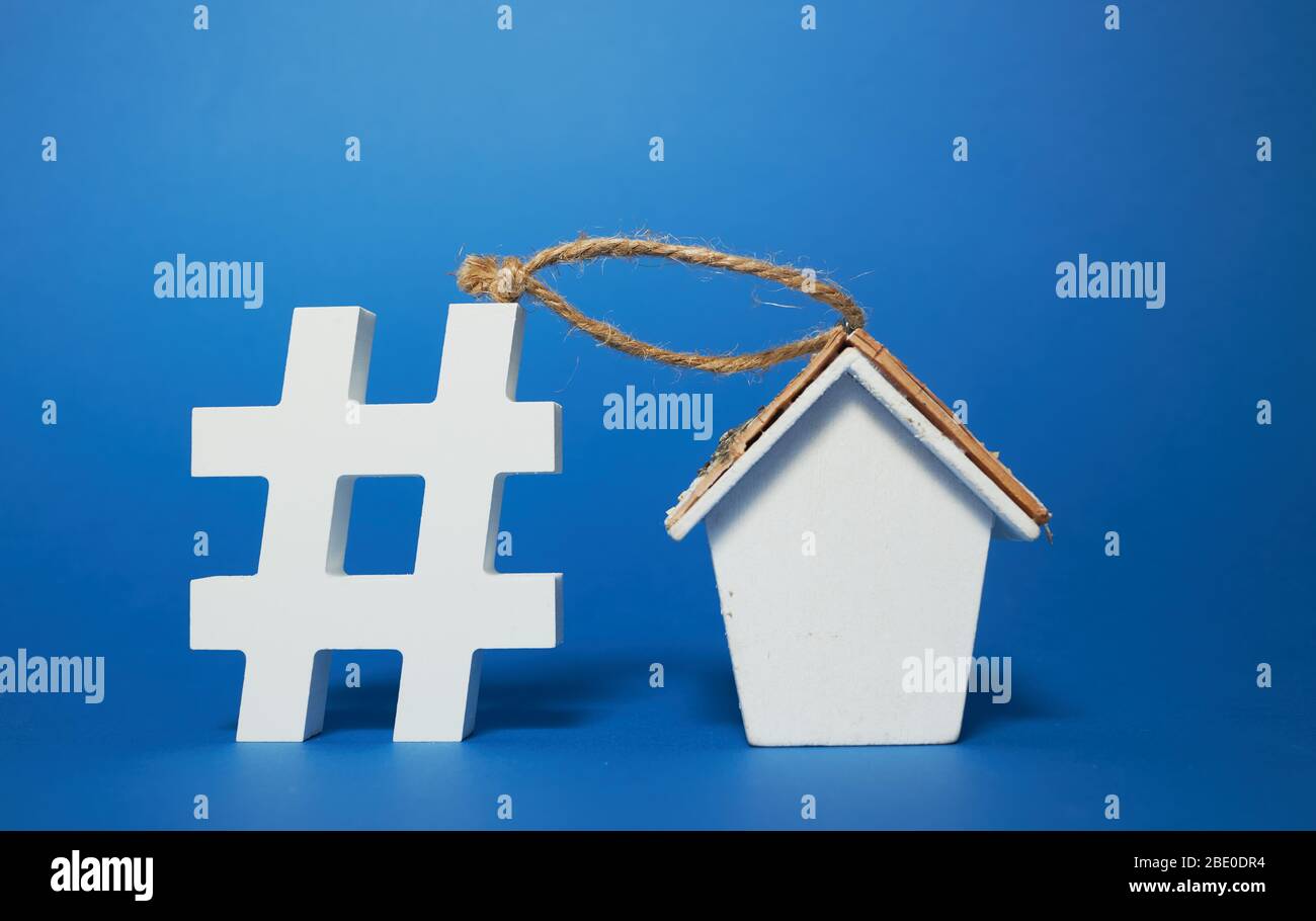 Stay home concept. Hashtag symbol and figurine of a wooden house on a ...