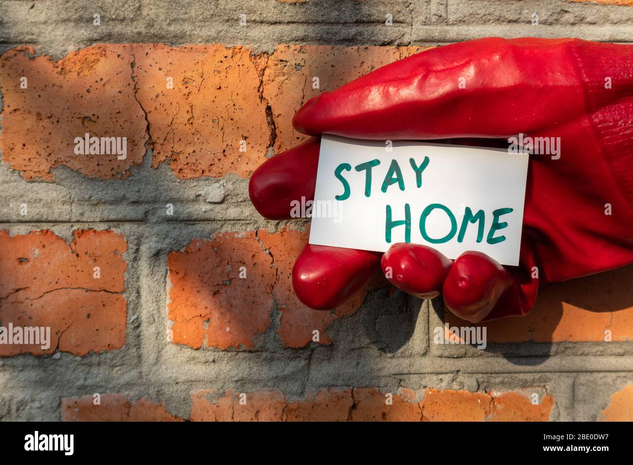 Stay home words on white card holding in red glove hand on sunny red ...