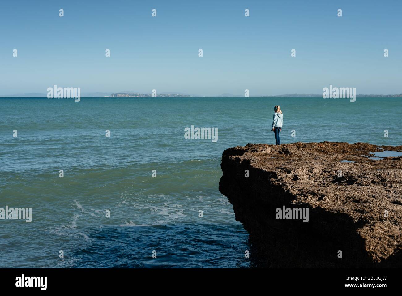 Tween girl standing on cliff overlooking ocean Stock Photo - Alamy